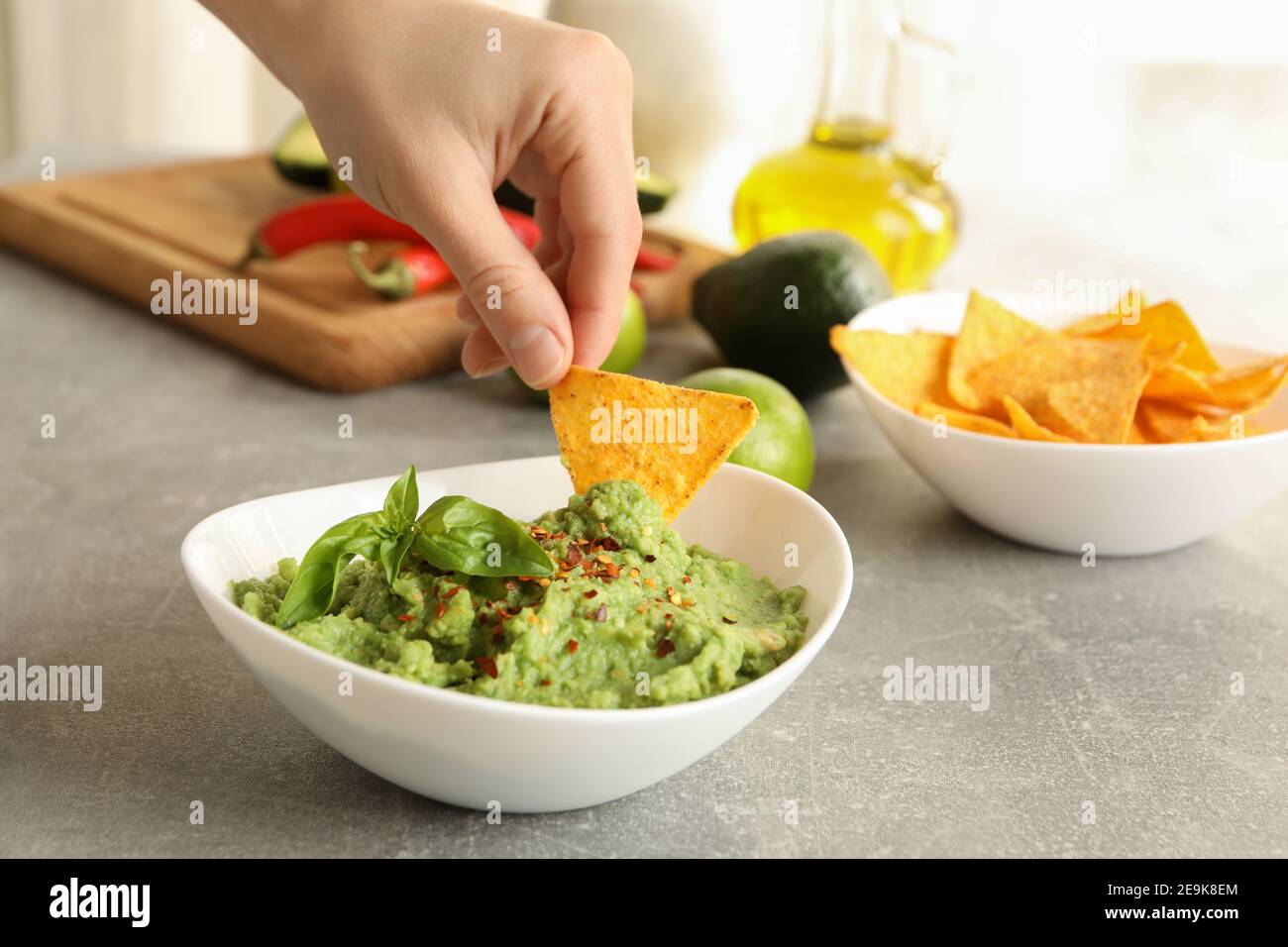 Female hand dips chips slice in guacamole Stock Photo - Alamy