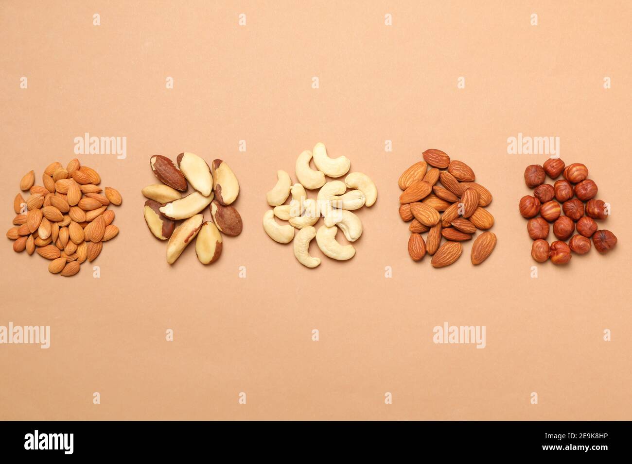 Set of different nuts on light beige background, top view Stock Photo ...