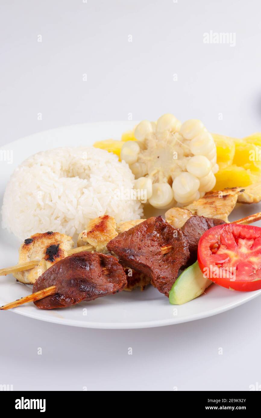 Peruvian dish called Anticucho with skewers of grilled chicken, rice ...