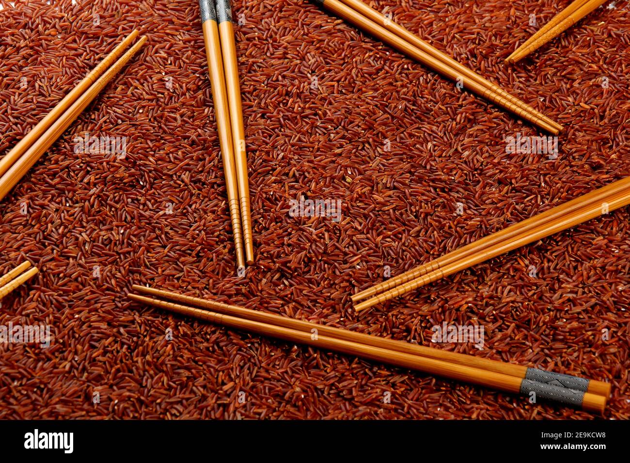 Raw red rice background with many Wooden chopsticks. uncooked brown ...