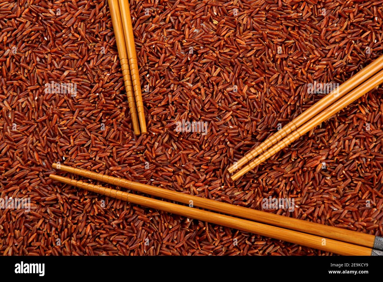 Raw red rice background with many Wooden chopsticks. uncooked brown ...