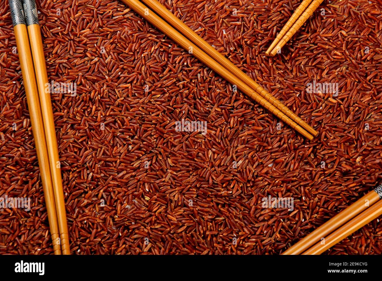 Raw red rice background with many Wooden chopsticks. uncooked brown ...