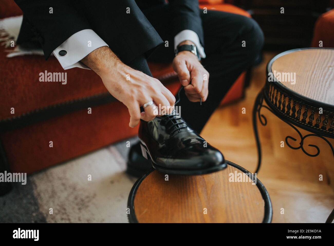 Elegant groom in a black suit tying his shoe on a wedding day Stock ...