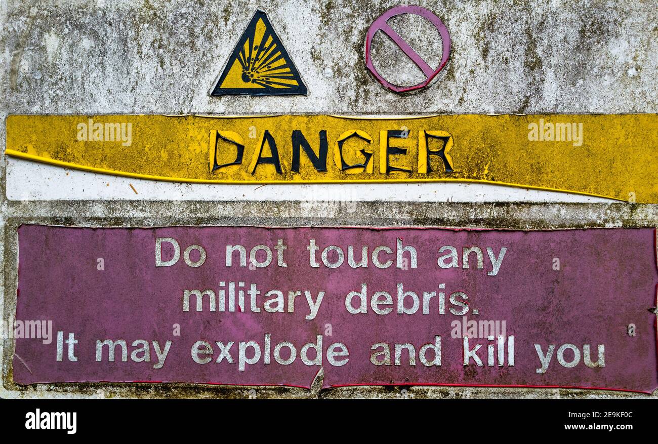 Weathered sign warning of danger of military debris that could explode ...