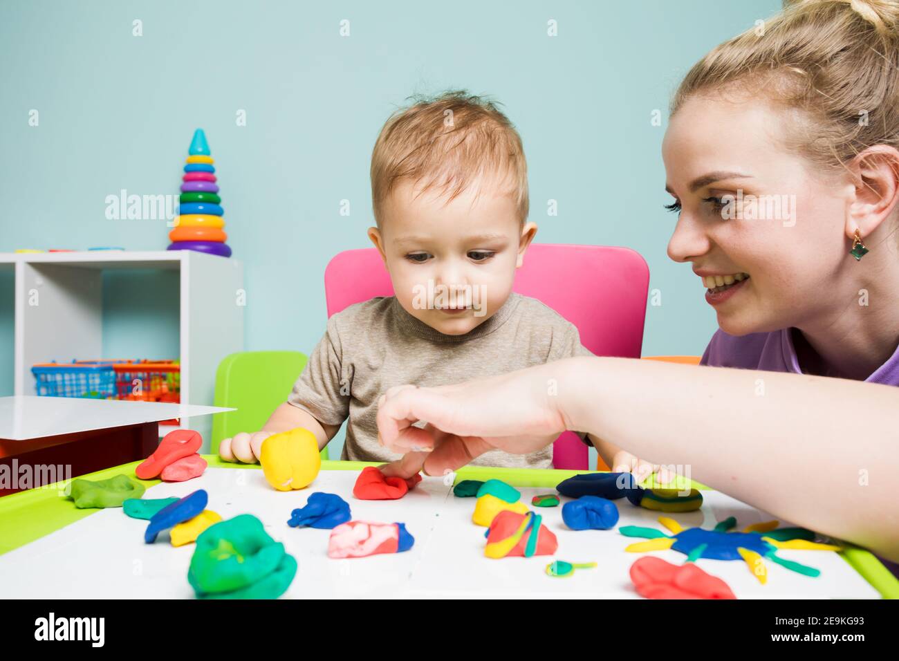 The young teacher and cute baby boy play with plasticine Stock Photo ...