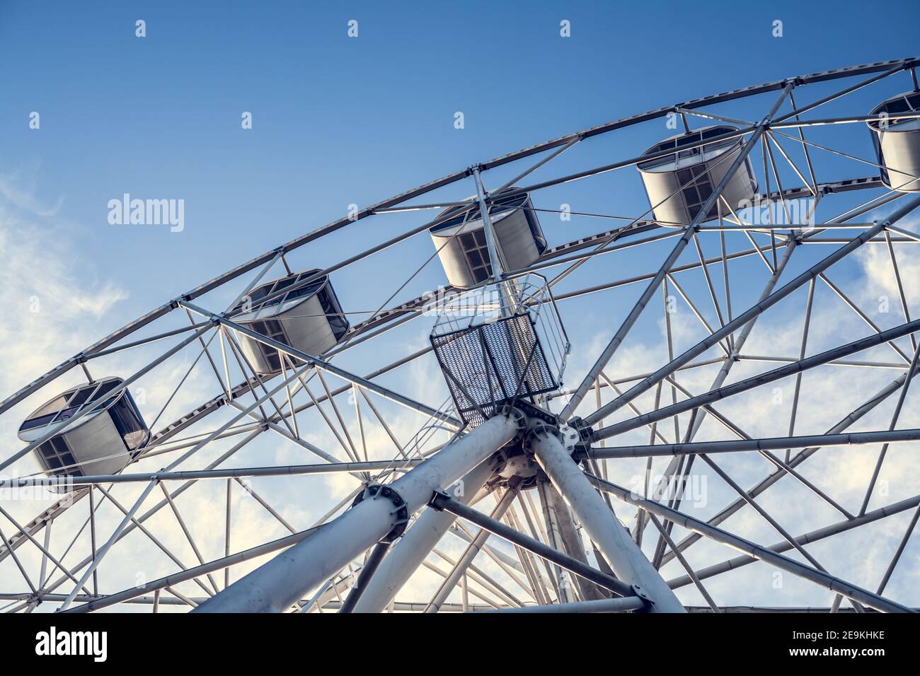 Gray or white metal ferris wheel with closed passenger cabins close-up ...