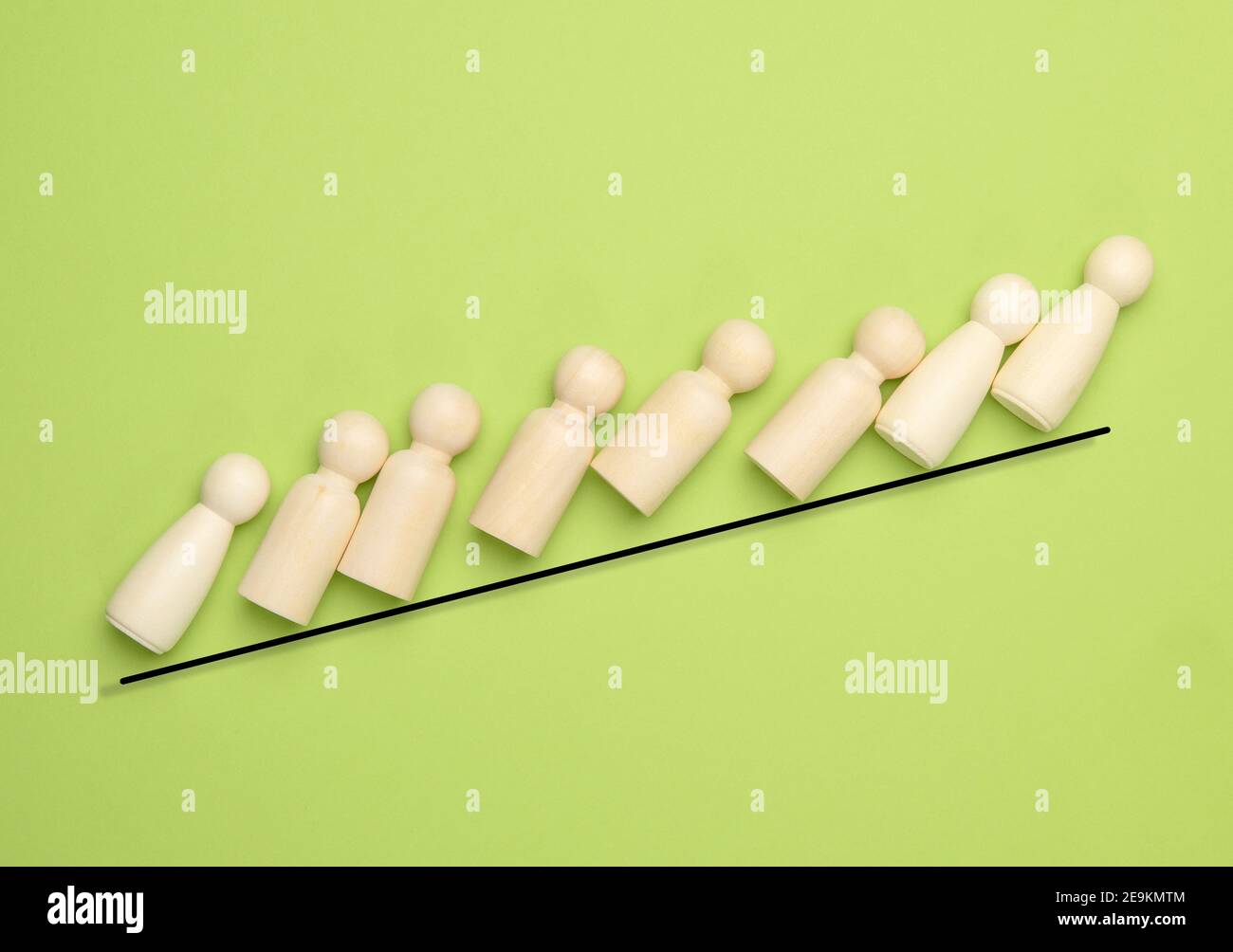 wooden figurines in the shape of a man climb up a steep line on a green ...