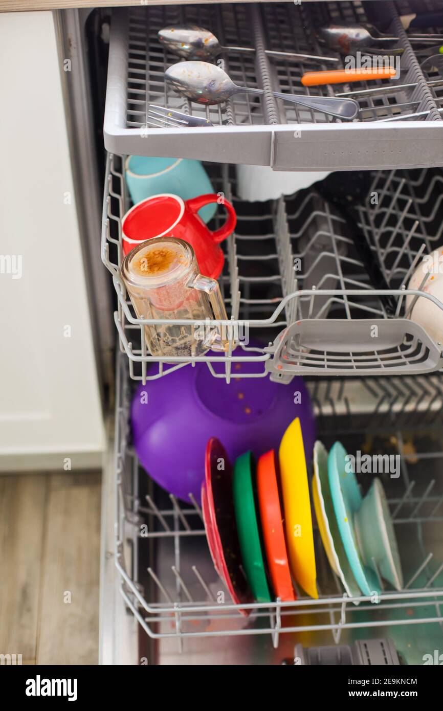 Putting dirty plates in the dishwasher after dinner Stock Photo - Alamy