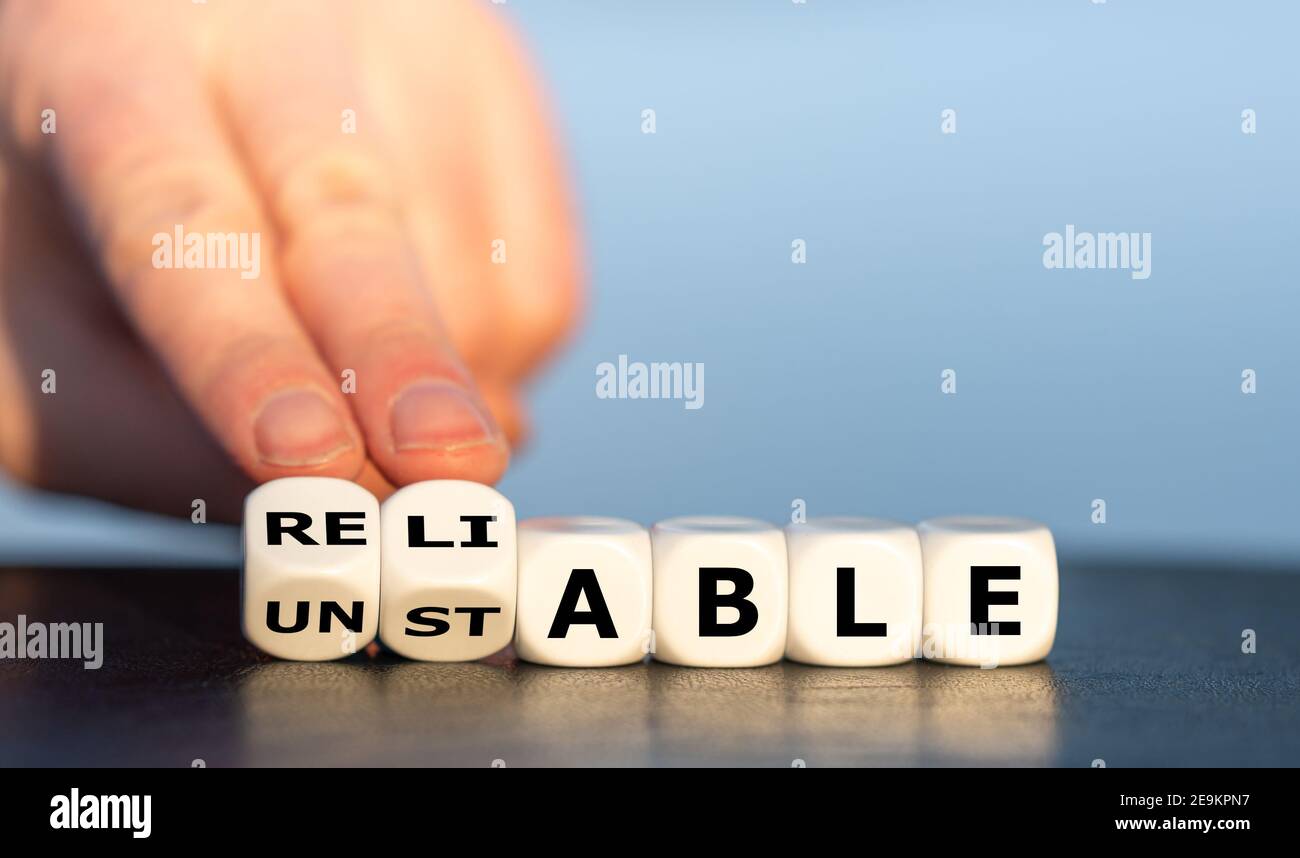 Hand turns dice and changes the word unstable to reliable Stock Photo ...
