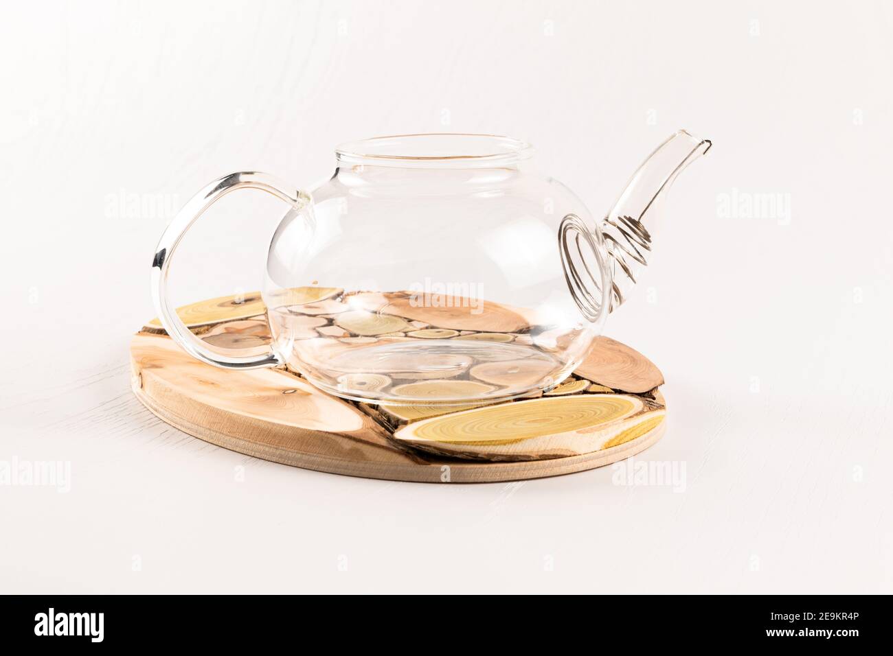 empty glass teapot on a wooden juniper stand on a white wooden table ...