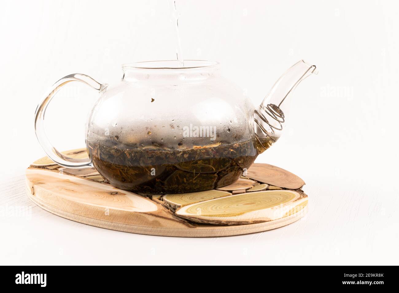 boiling water is poured into a glass teapot with aromatic herbal tea ...