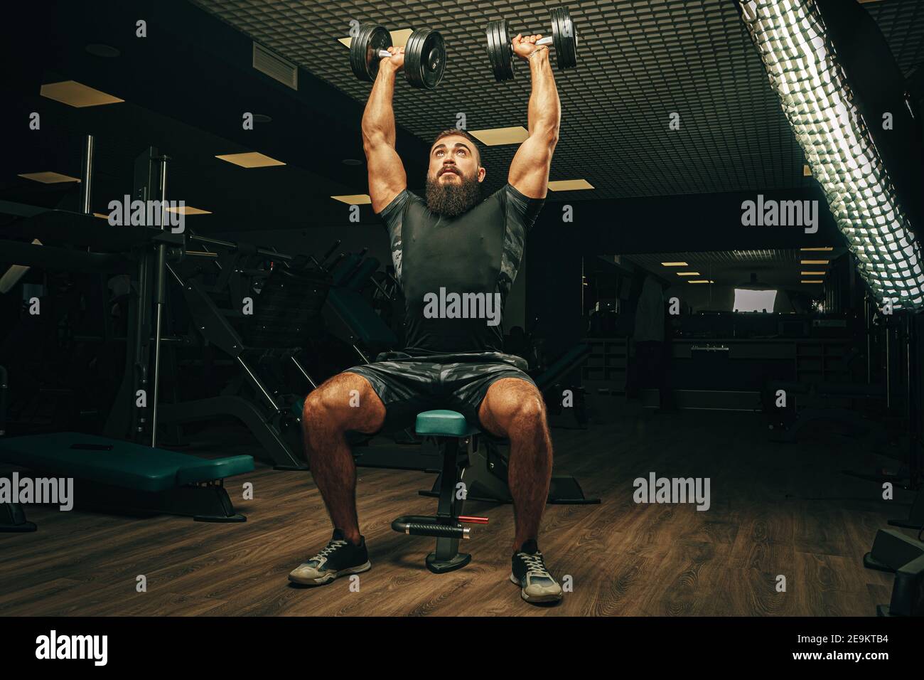 Bodybuilder doing exercises with dumbbells in a dark gym Stock Photo ...