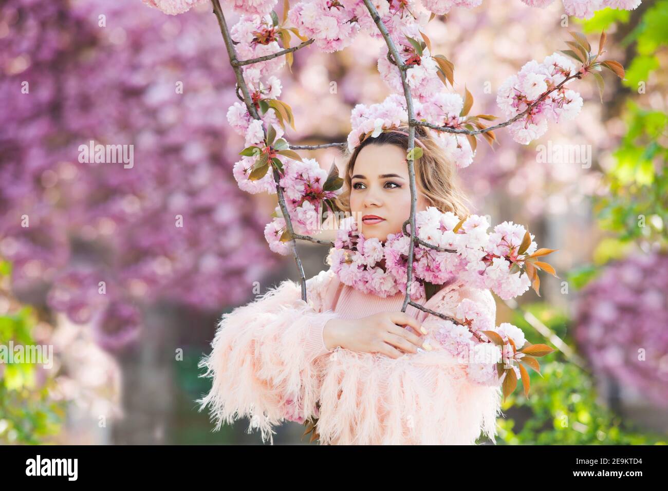 the girl is standing under the pink tree that bloom Stock Photo - Alamy