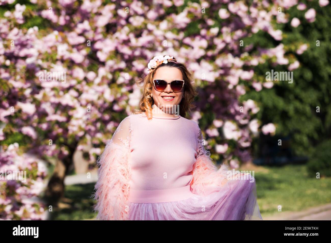 the girl is standing under the pink tree that bloom Stock Photo - Alamy