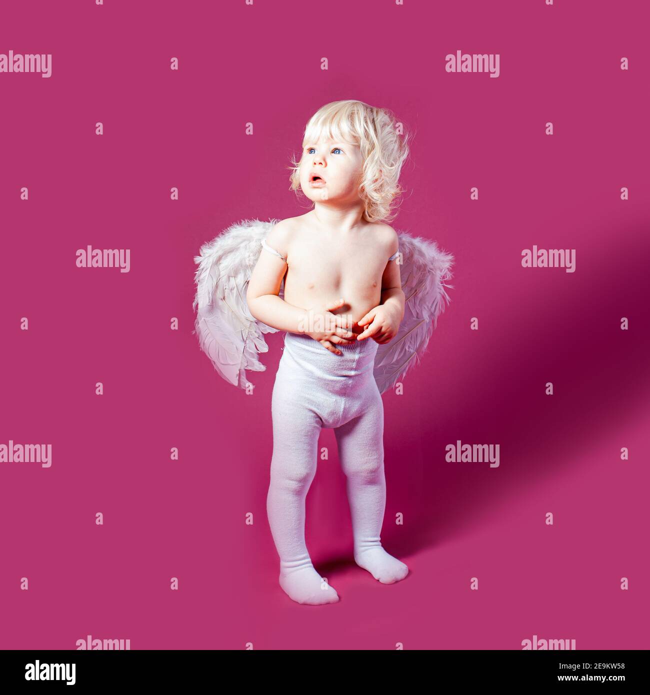 Toddler wearing angel feather wings and stand on the pink Stock Photo ...