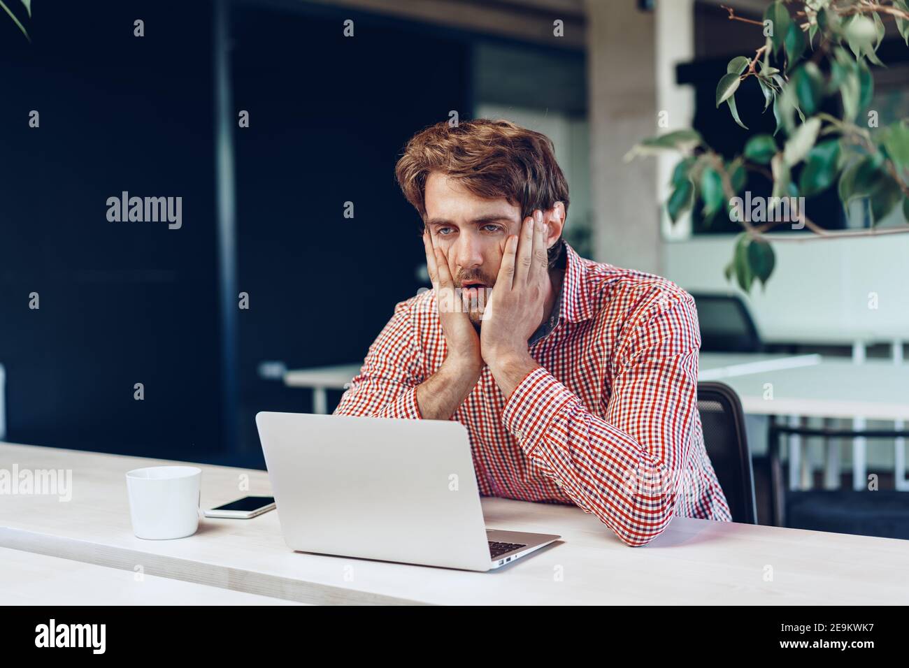 Tired businessman working on his computer in open space office Stock ...