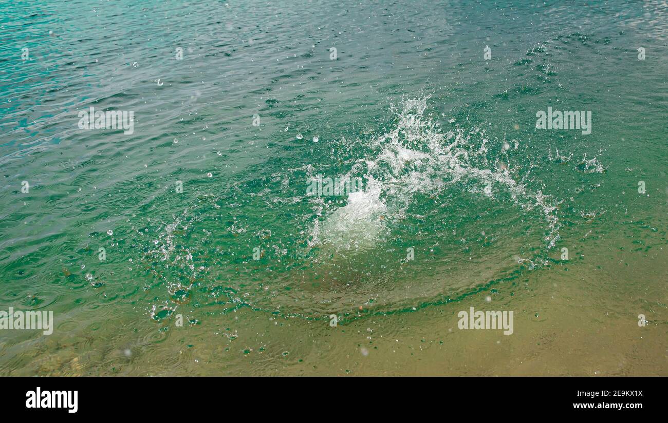 Splashes, ripples, circles created by stones thrown into the sea, drop ...