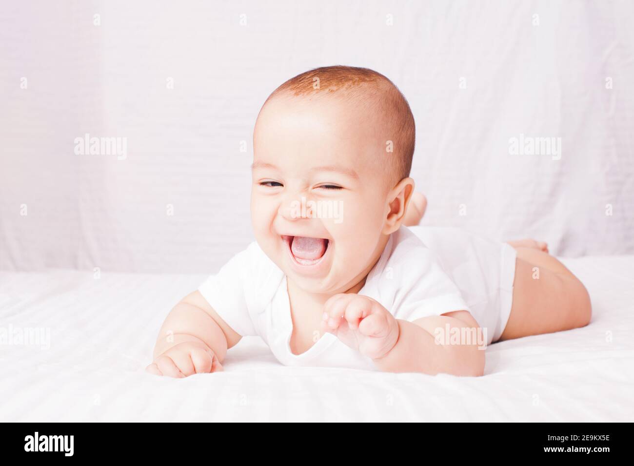 Adorable baby lying on the stomach at the white Stock Photo - Alamy