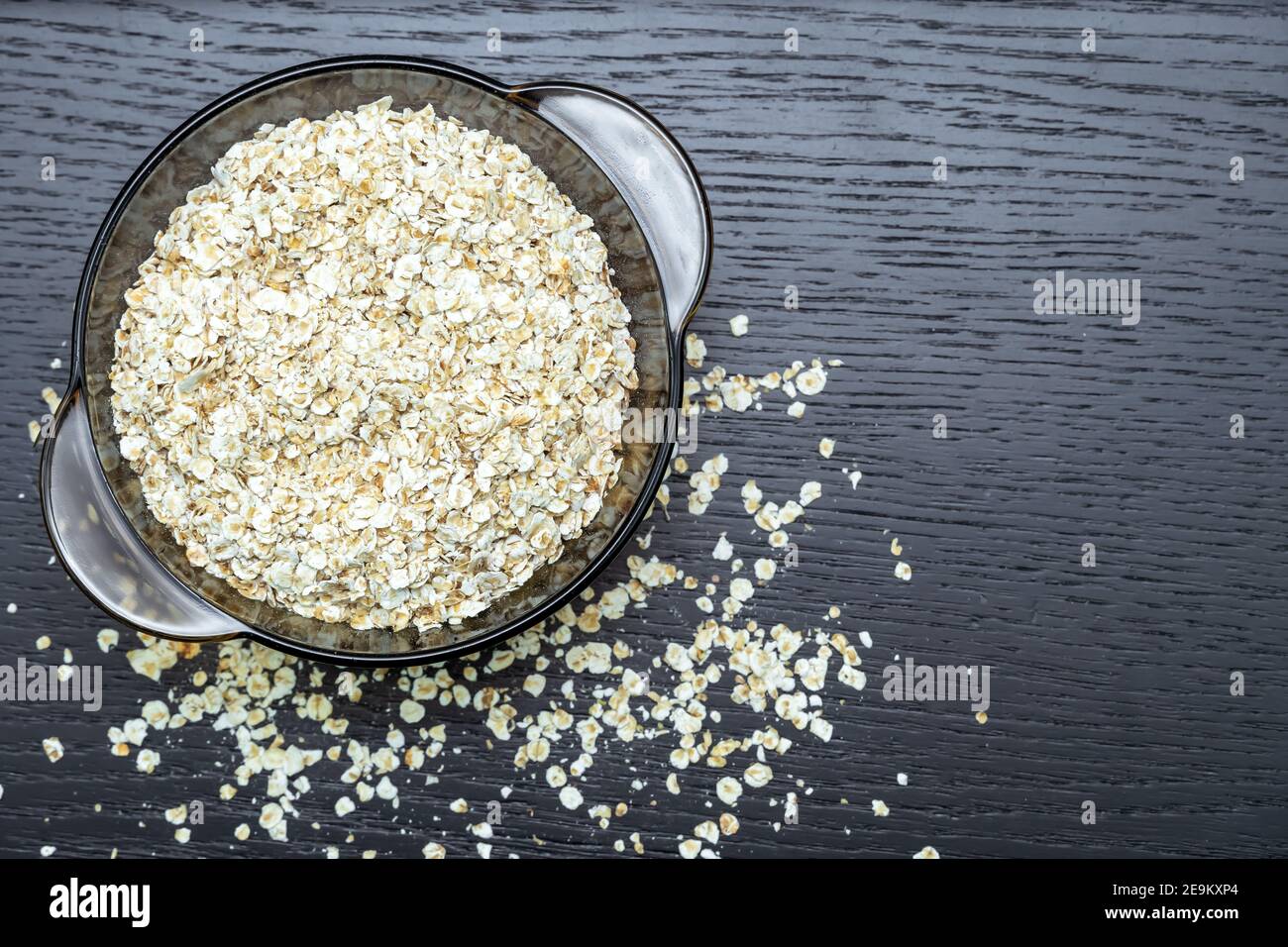 Dry oatmeal porridge in a transparent bowl on a dark background with ...