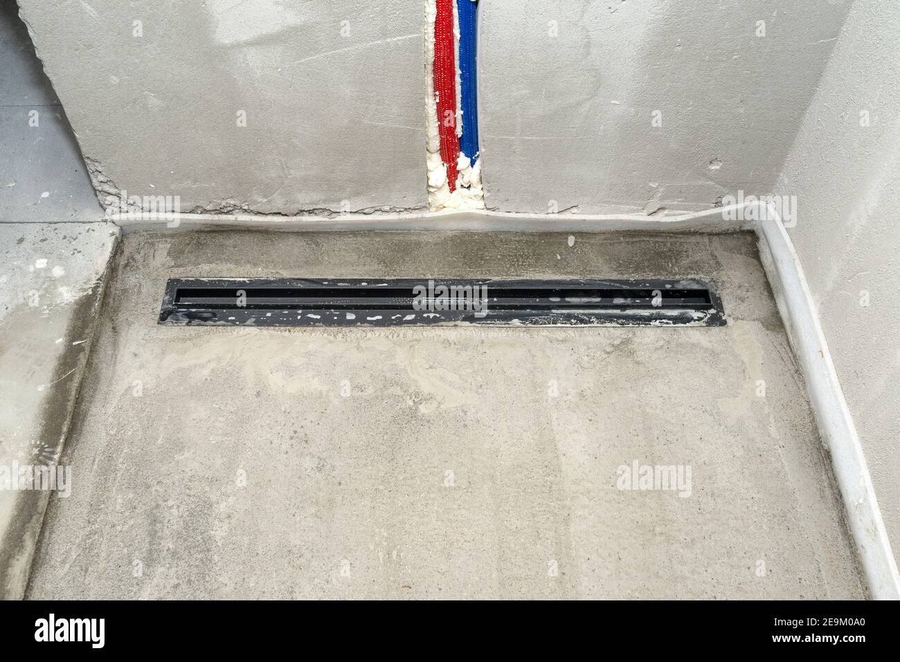 A modern black linear shower drain installed in the shower floor ...