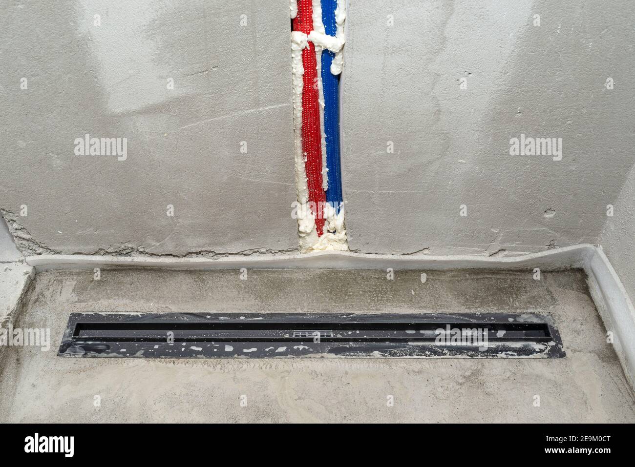 A modern black linear shower drain installed in the shower floor ...