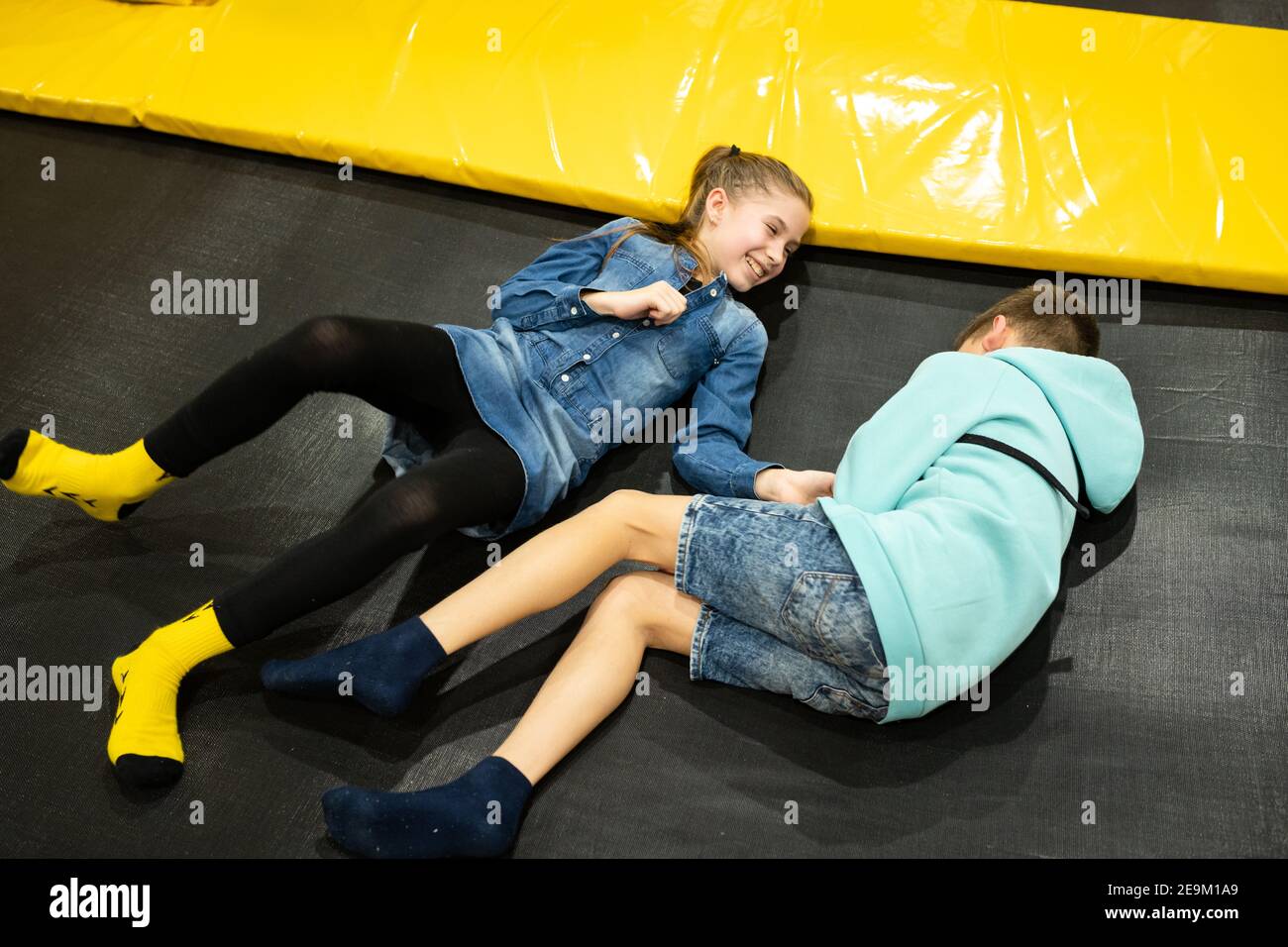 Cute twin brother and sister jumping and bouncing on indoor trampoline ...