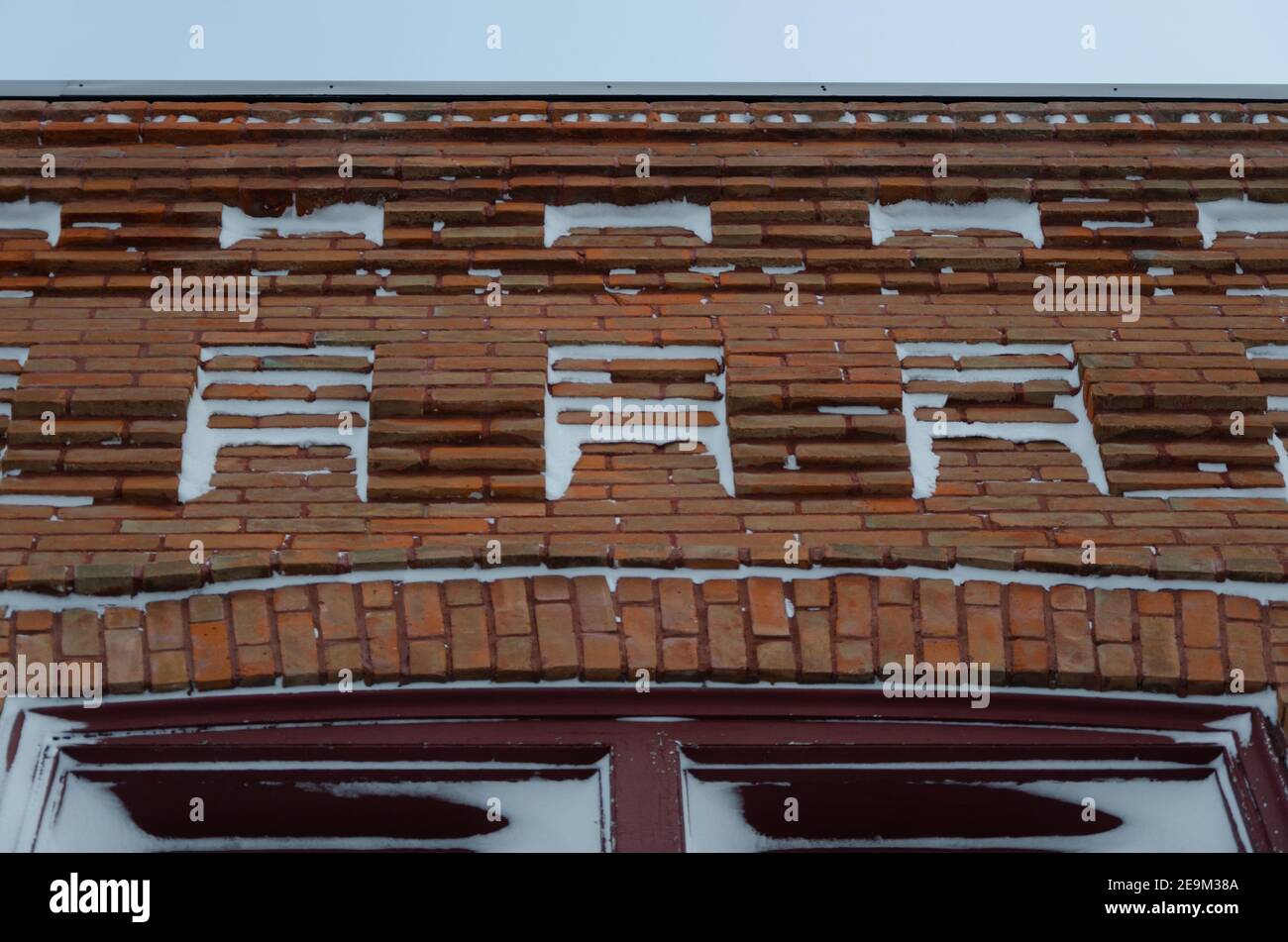 Low angle of a building with a red brick wall covered in snow in winter ...