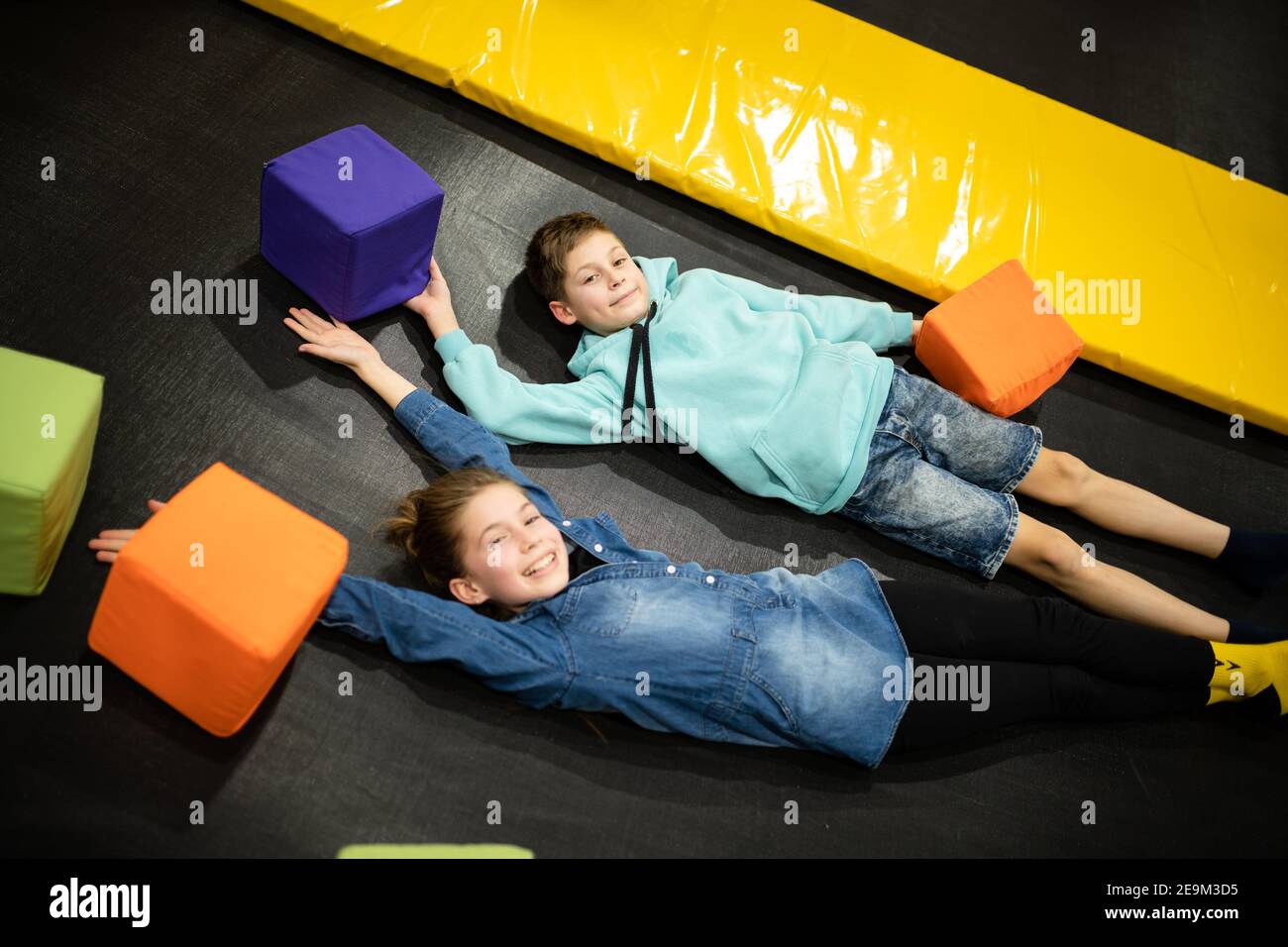 Cute twin brother and sister jumping and bouncing on indoor trampoline ...