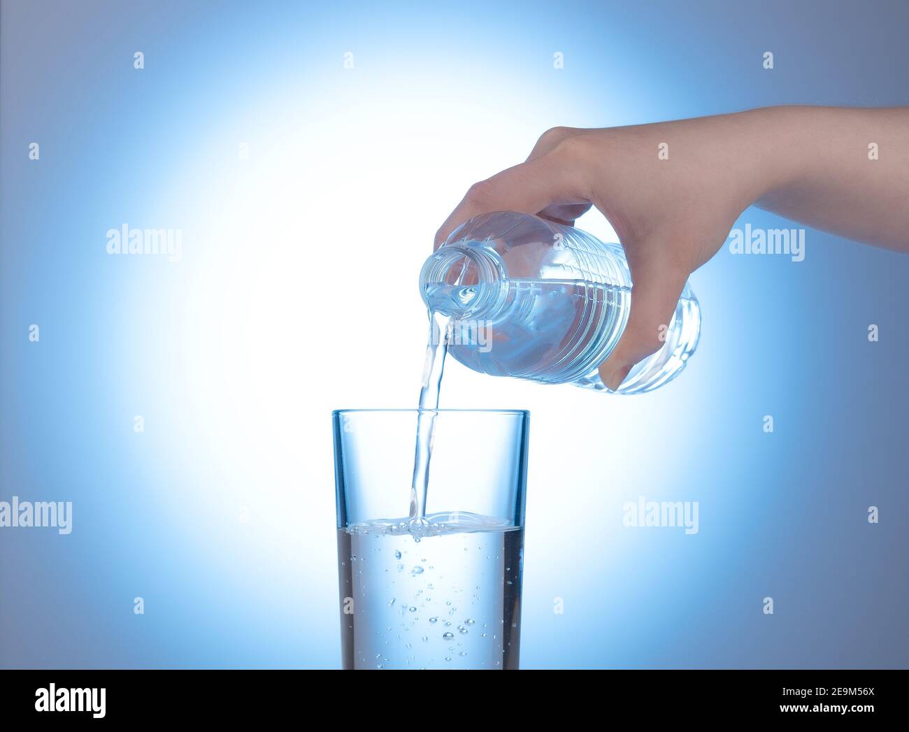 Plastic bottle with mineral water in a female hand. Pour water into a ...