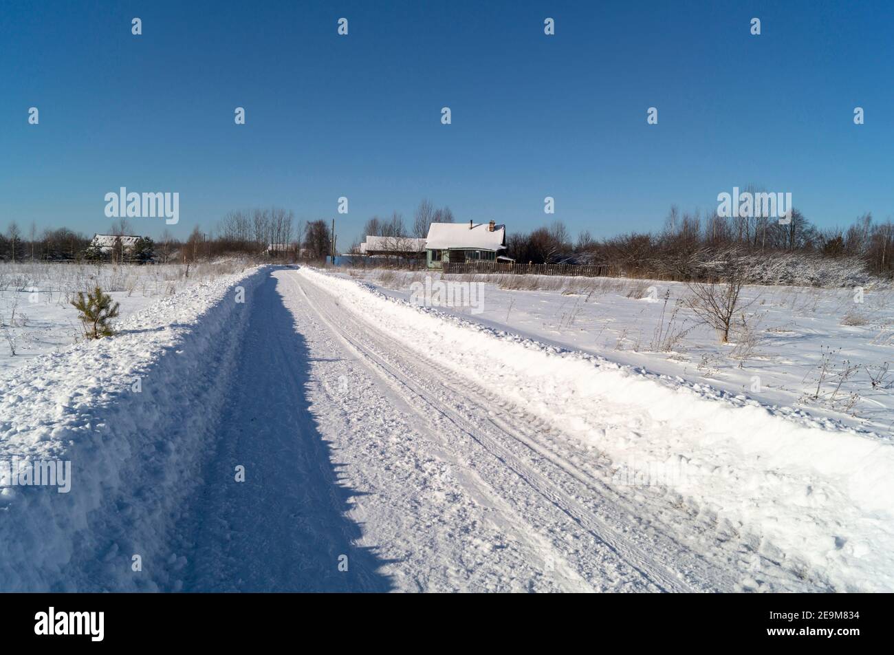 The Winter road through field in village on background blue sky ...