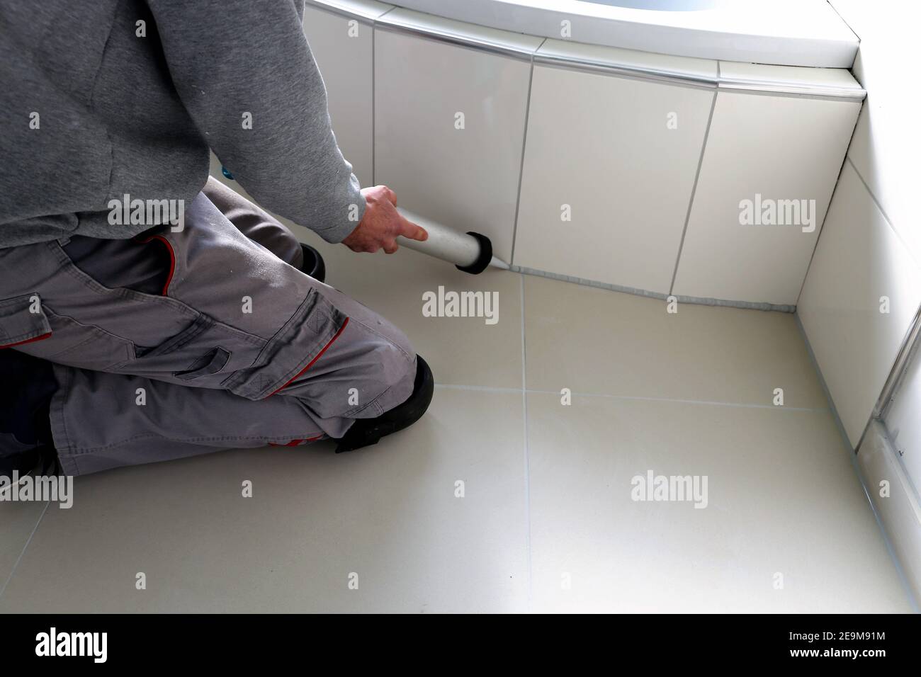 Grouting work. Tiler grouting in a new bathroom Stock Photo - Alamy