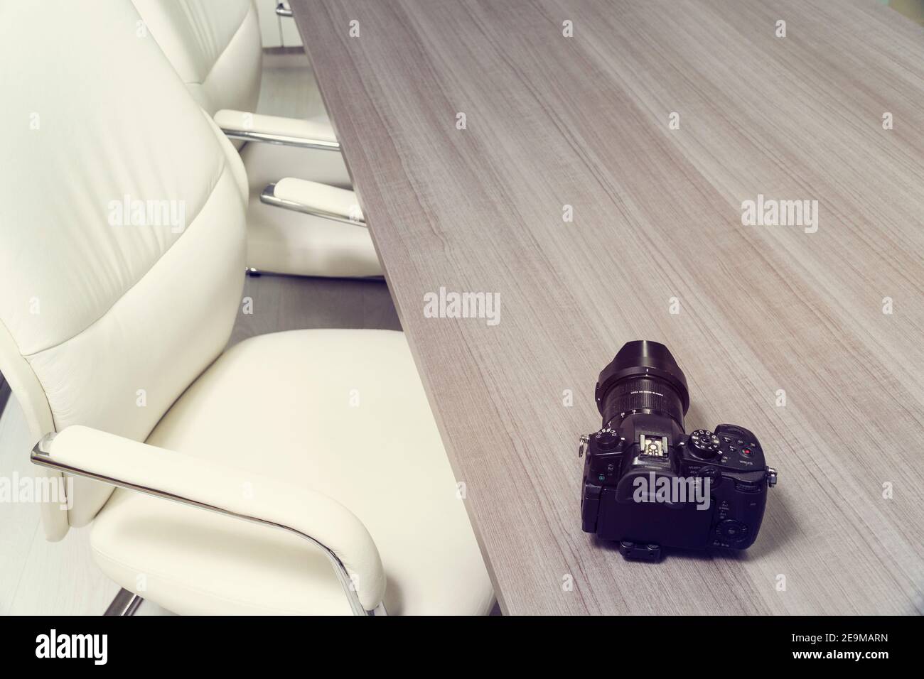 Photographic camera on an office table with some white seats on the ...