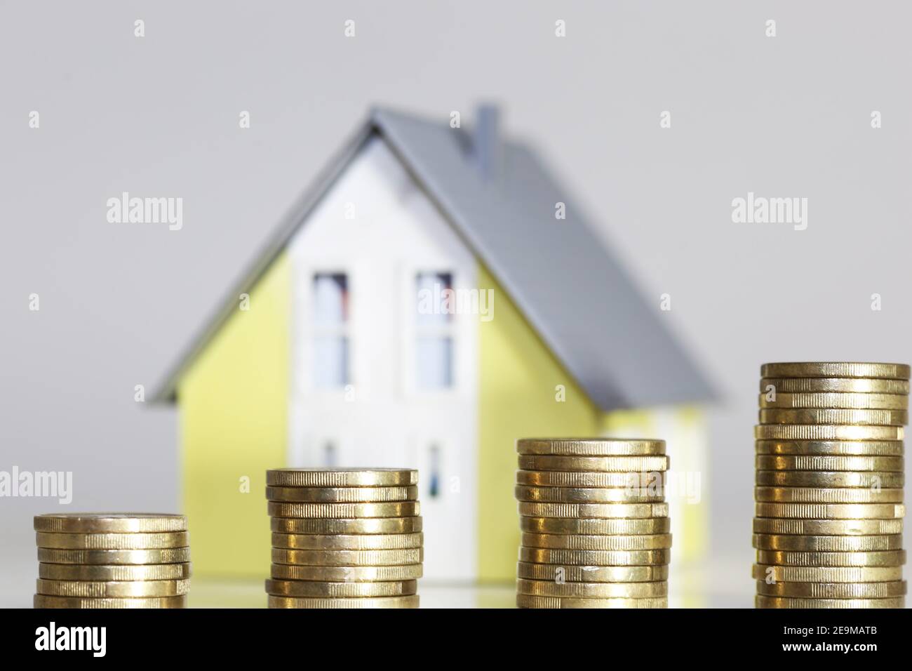 Symbol image with model house and money coins Stock Photo - Alamy