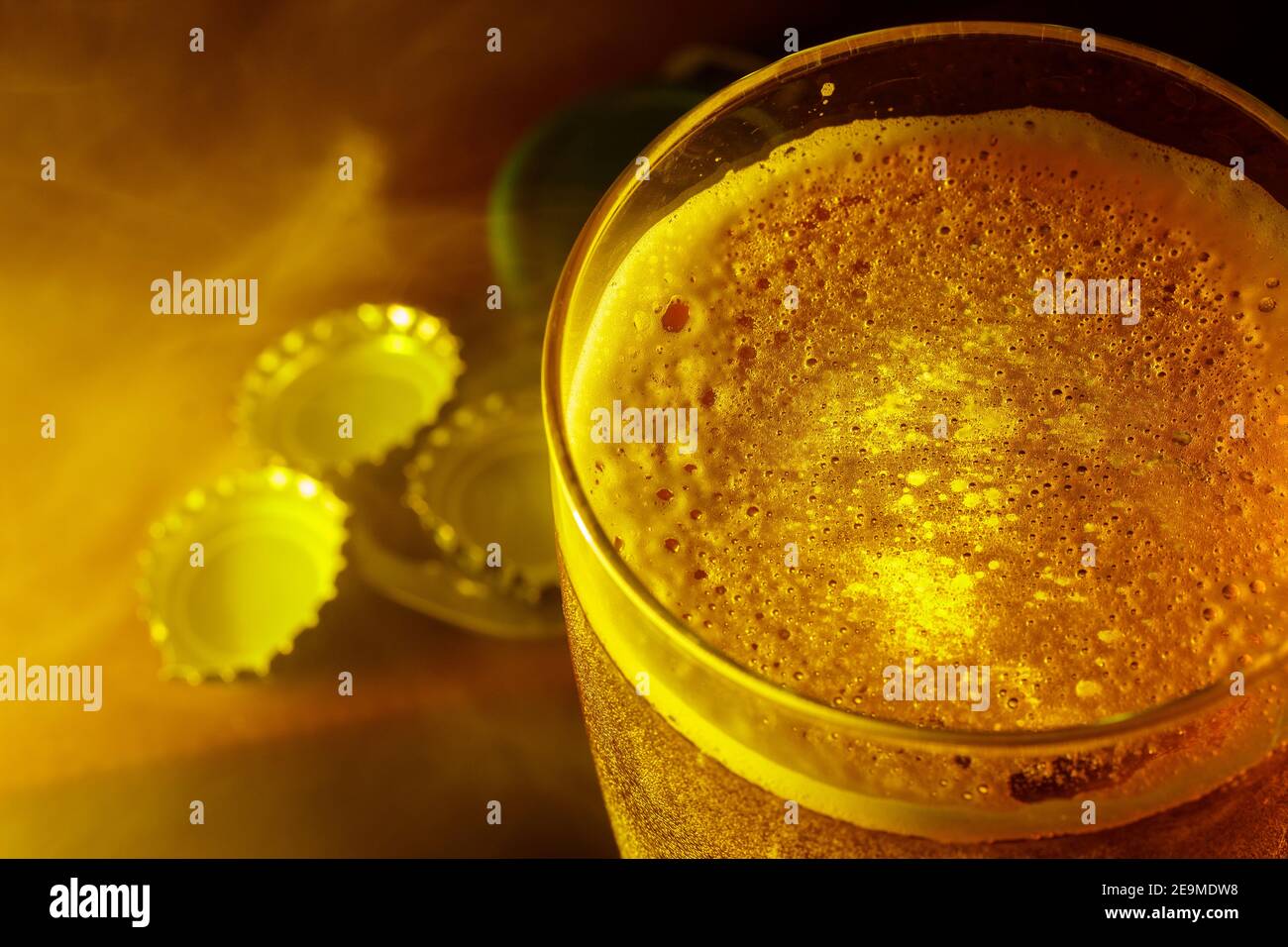 Glass of beer seen up close with beer bottle caps and a corkscrew Stock ...