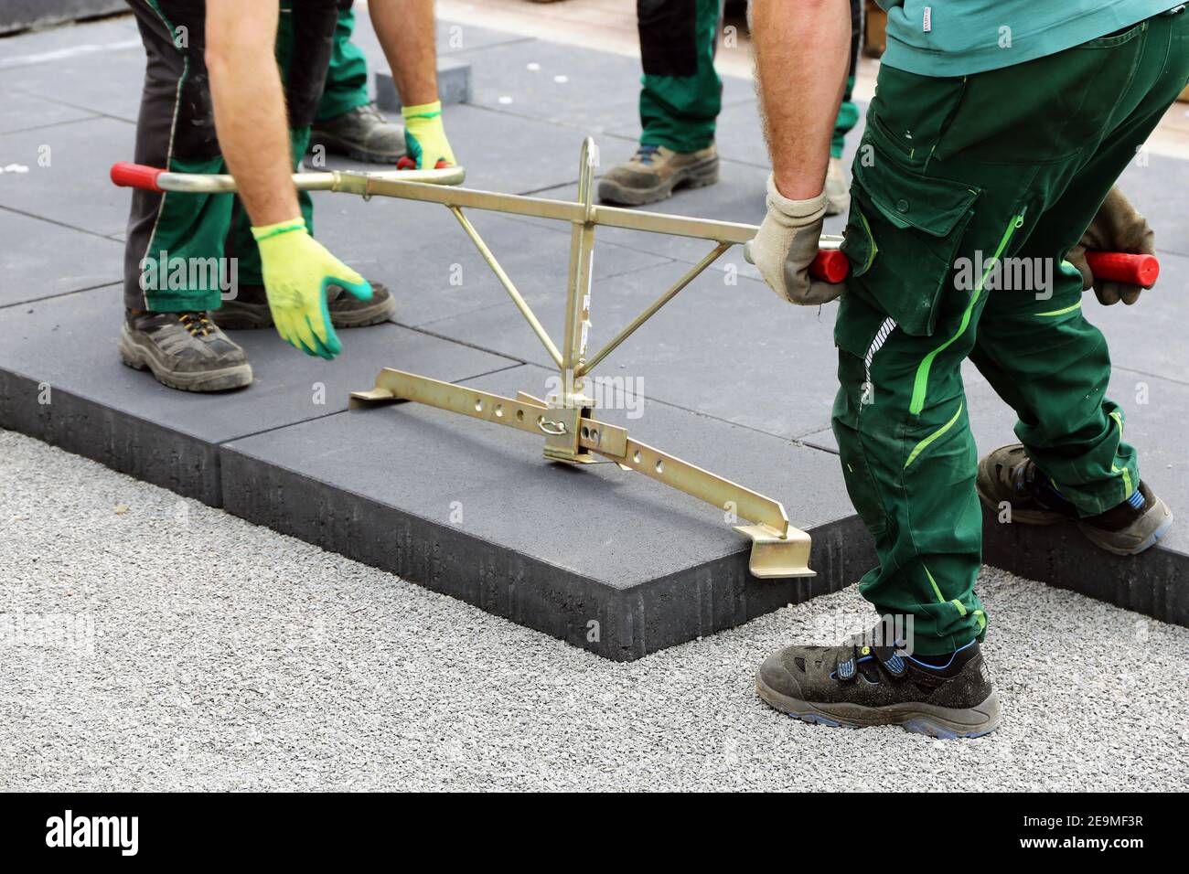 Construction workers lay heavy paving stones with a stone lifter Stock ...
