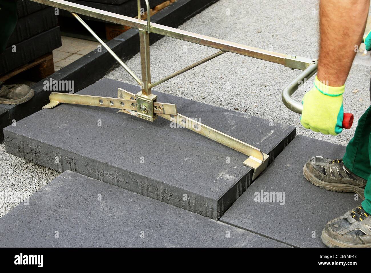 Construction workers lay heavy paving stones with a stone lifter Stock ...