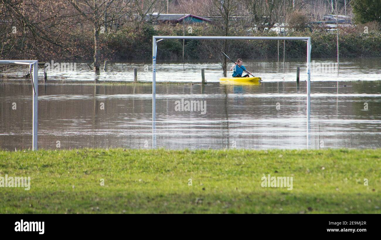 Surreal scene with a man rowing in a boat on a flooded football field ...