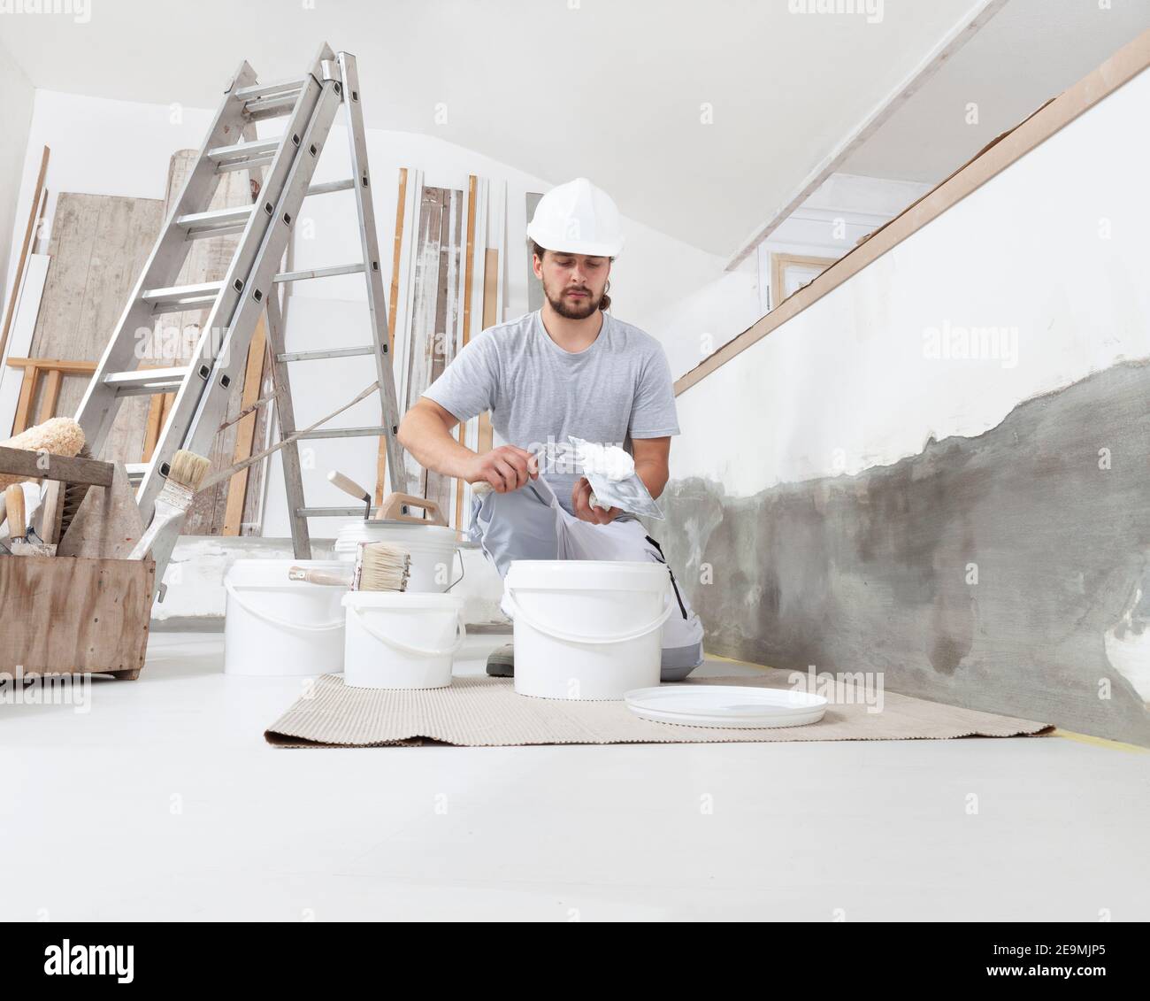 man plasterer construction worker at work, takes plaster from bucket ...