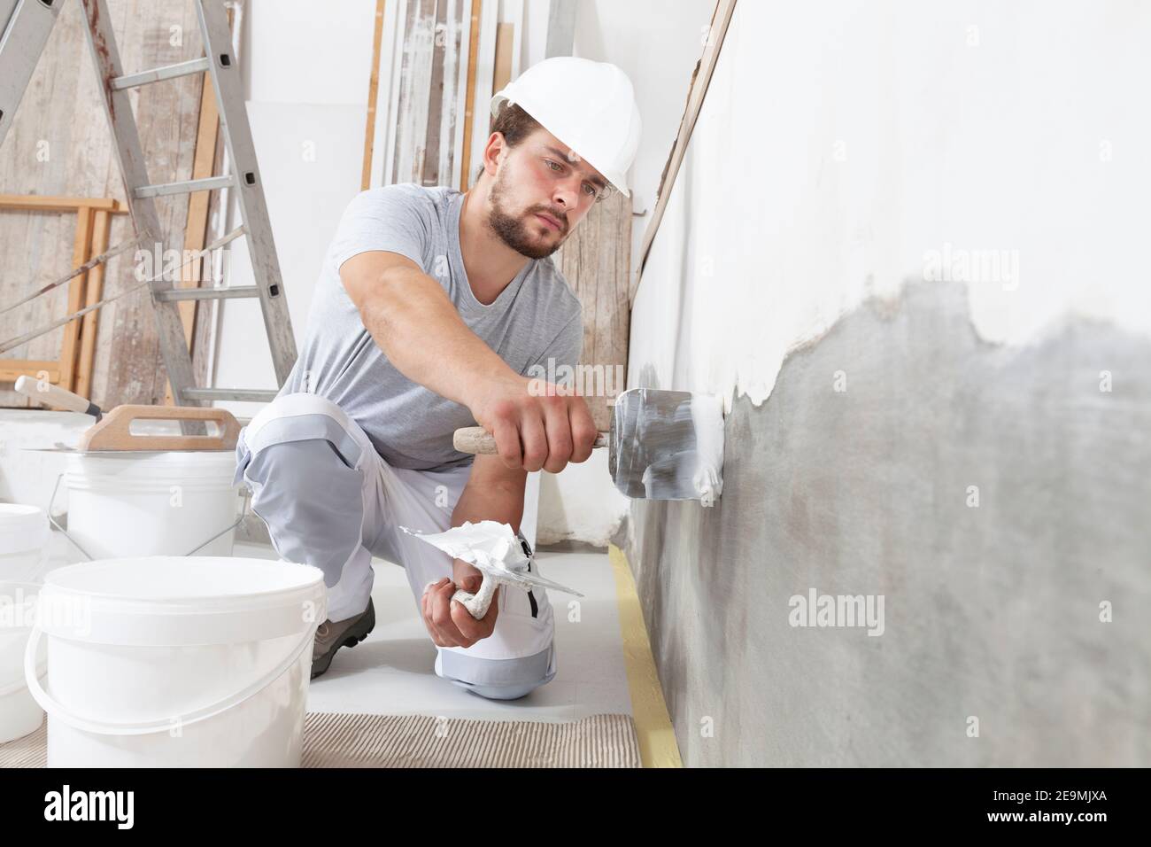 man plasterer construction worker at work, takes plaster from bucket ...