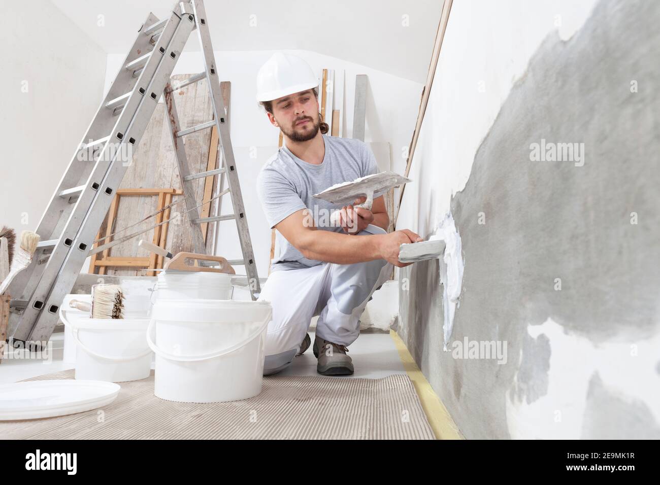 man plasterer construction worker at work, takes plaster from bucket ...