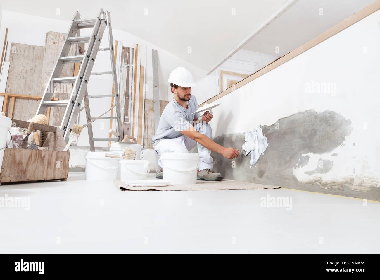 man plasterer construction worker at work, takes plaster from bucket ...