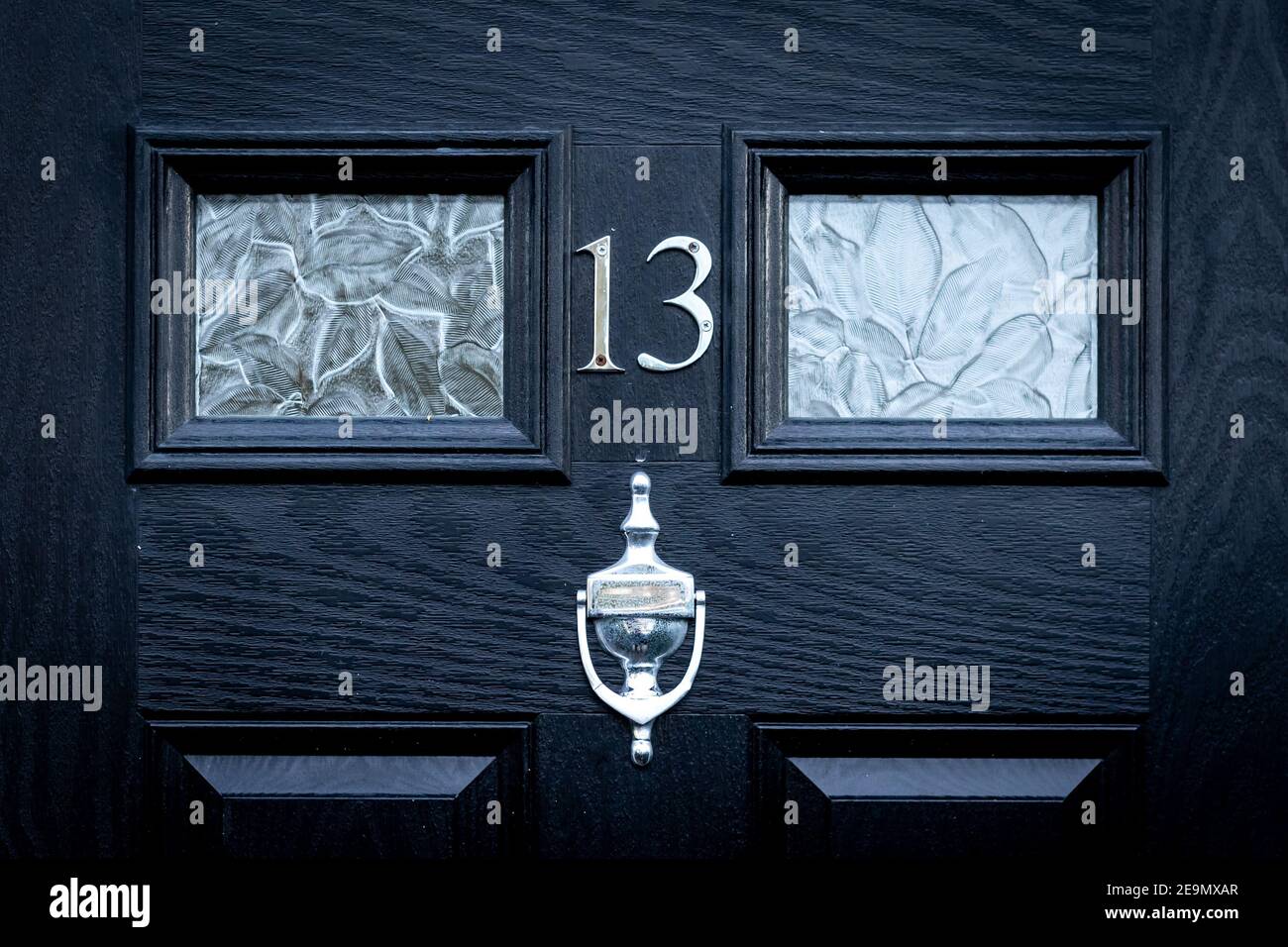 House number 13 in silver metal digit on a black wooden front door ...