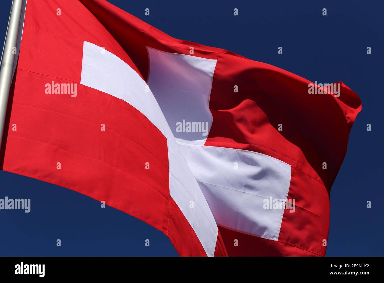 The flag of Switzerland during a windy day. Closeup of the red and ...