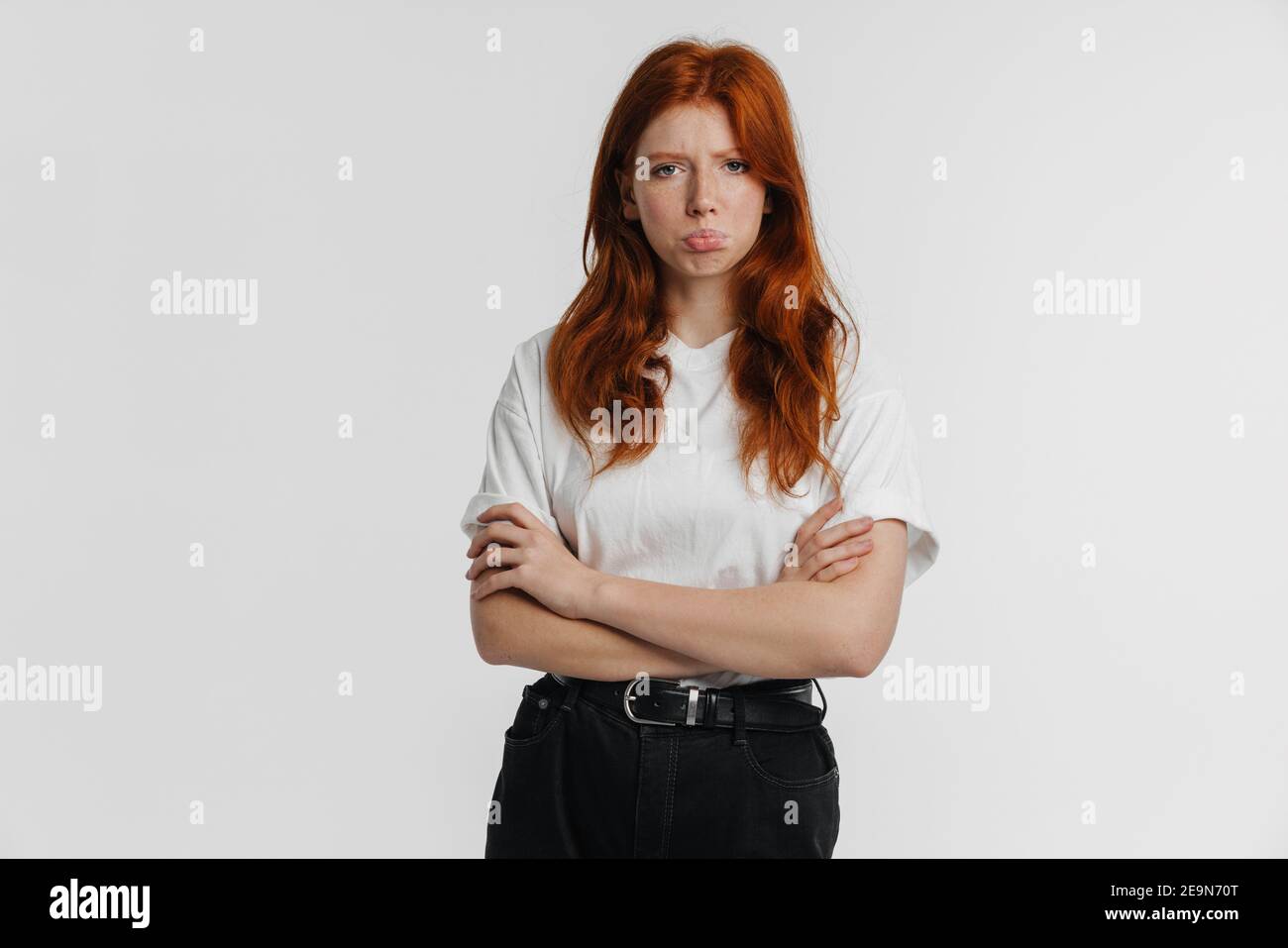 Ginger beautiful unhappy girl grimacing while posing with arms crossed ...