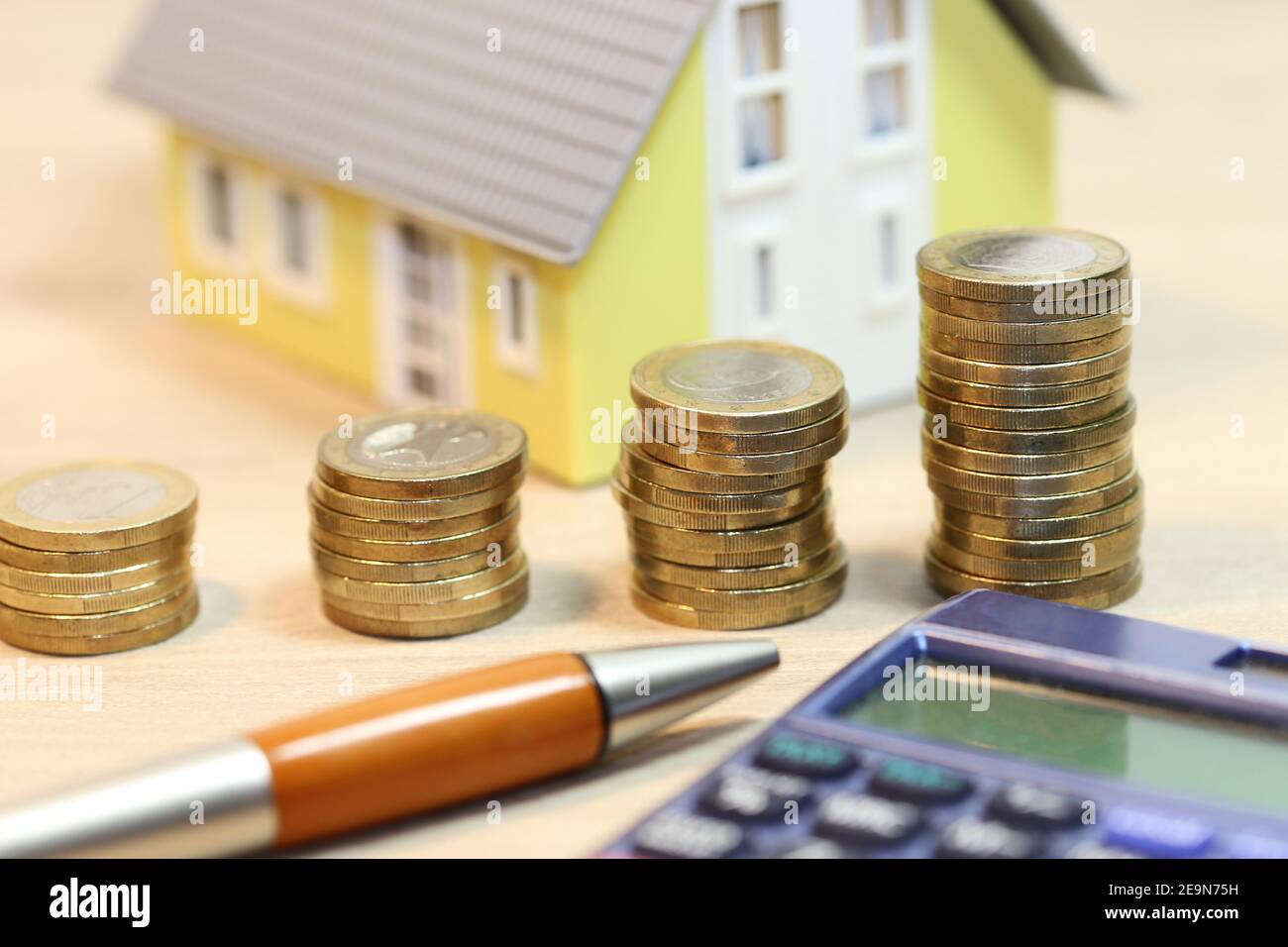Symbol image with model house and money coins Stock Photo - Alamy