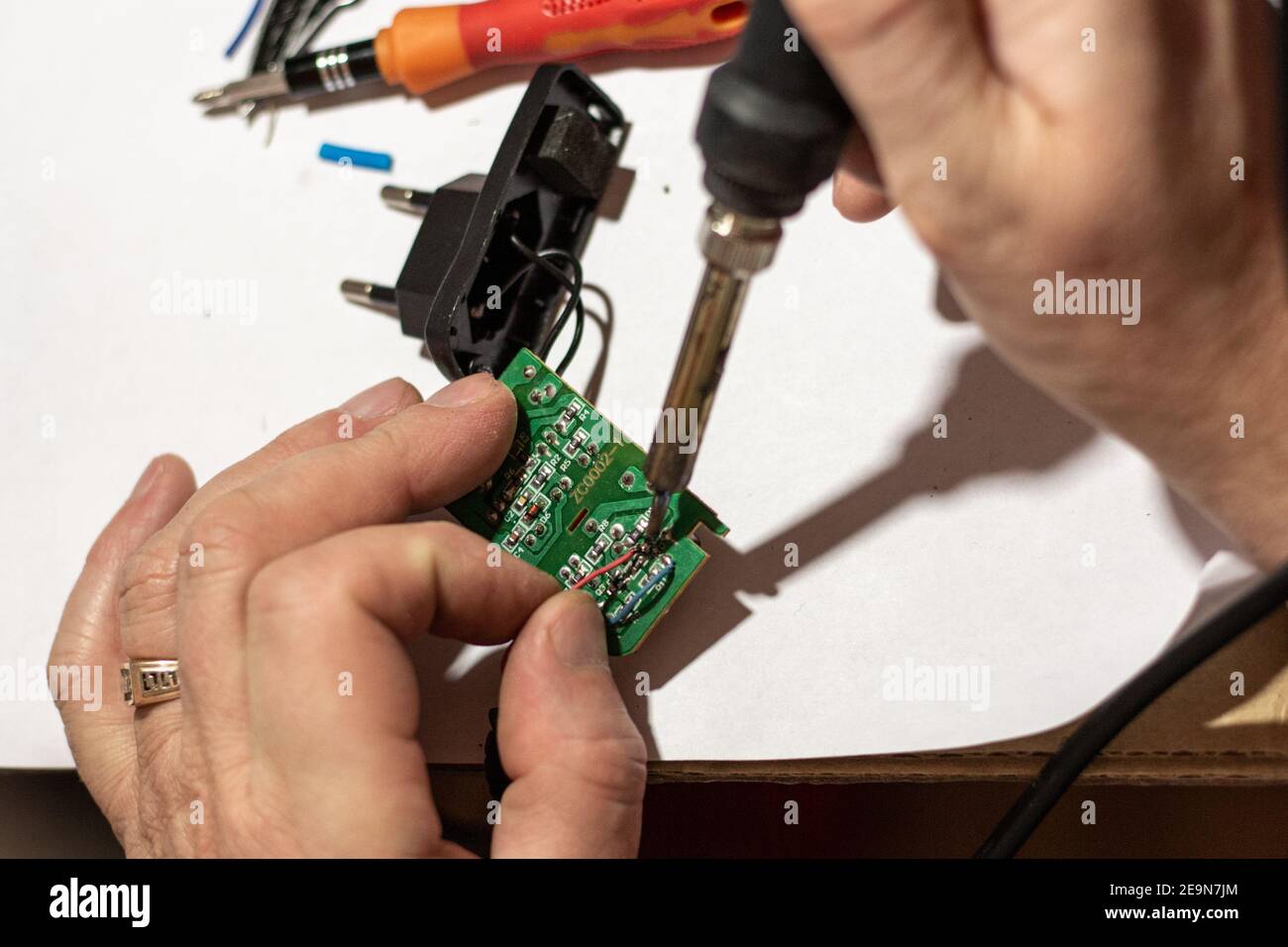 the hands of the worker hold a soldering iron, with which he solders ...