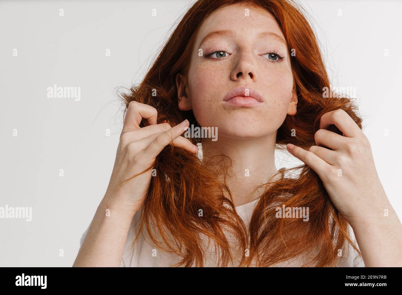 Ginger Beautiful Serious Girl Posing And Doing Her Hair Isolated Over