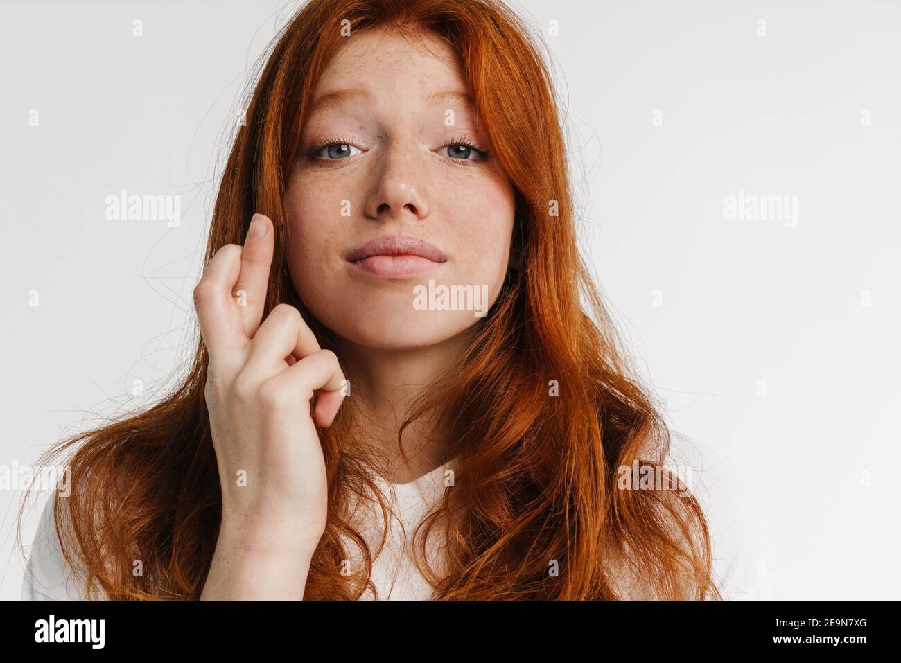 Ginger beautiful pleased girl holding fingers crossed for good luck ...