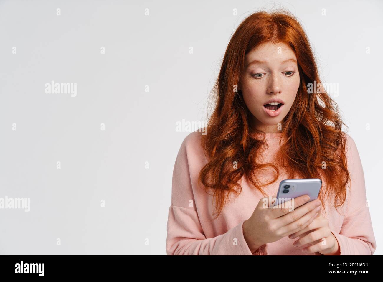 Ginger nice shocked girl posing and using mobile phone isolated over white background Stock ...