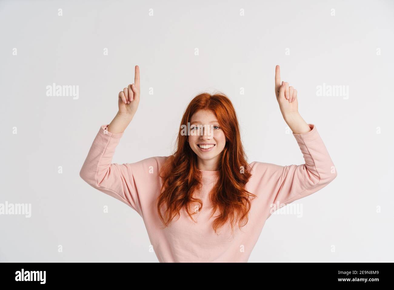 Ginger beautiful happy girl smiling and pointing fingers upward ...